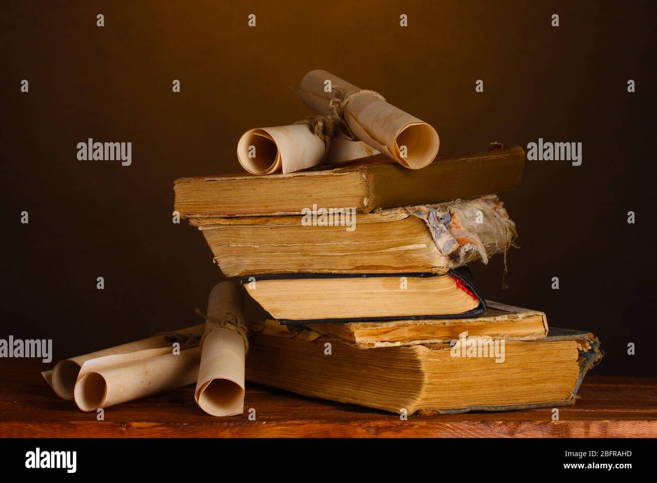 Pile of old books and scroll on brown Stock Photo - Alamy