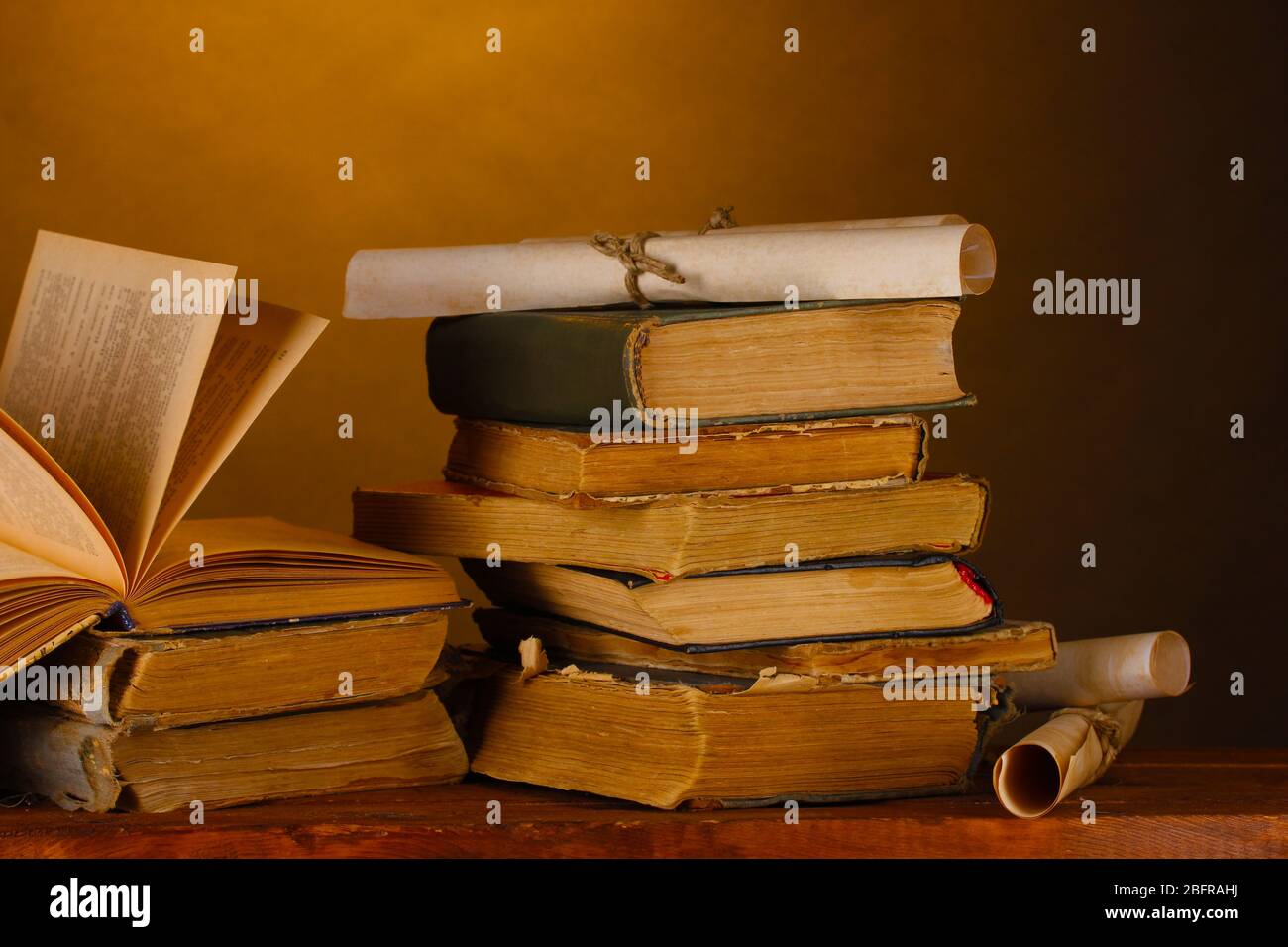 Pile of old books and scroll on brown Stock Photo - Alamy