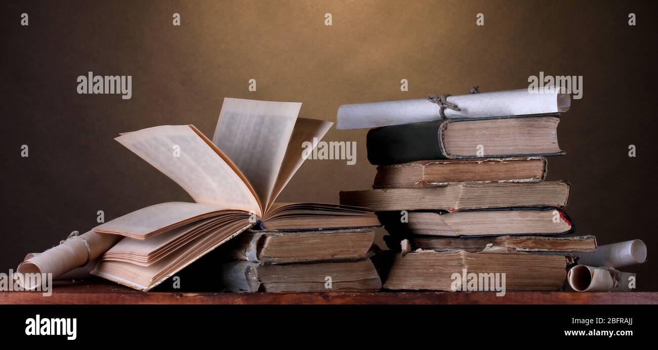 Pile of old books and scroll on brown Stock Photo - Alamy