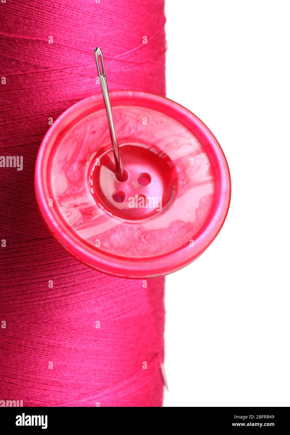 Pink bobbin thread with needle and pink button isolated on white Stock ...