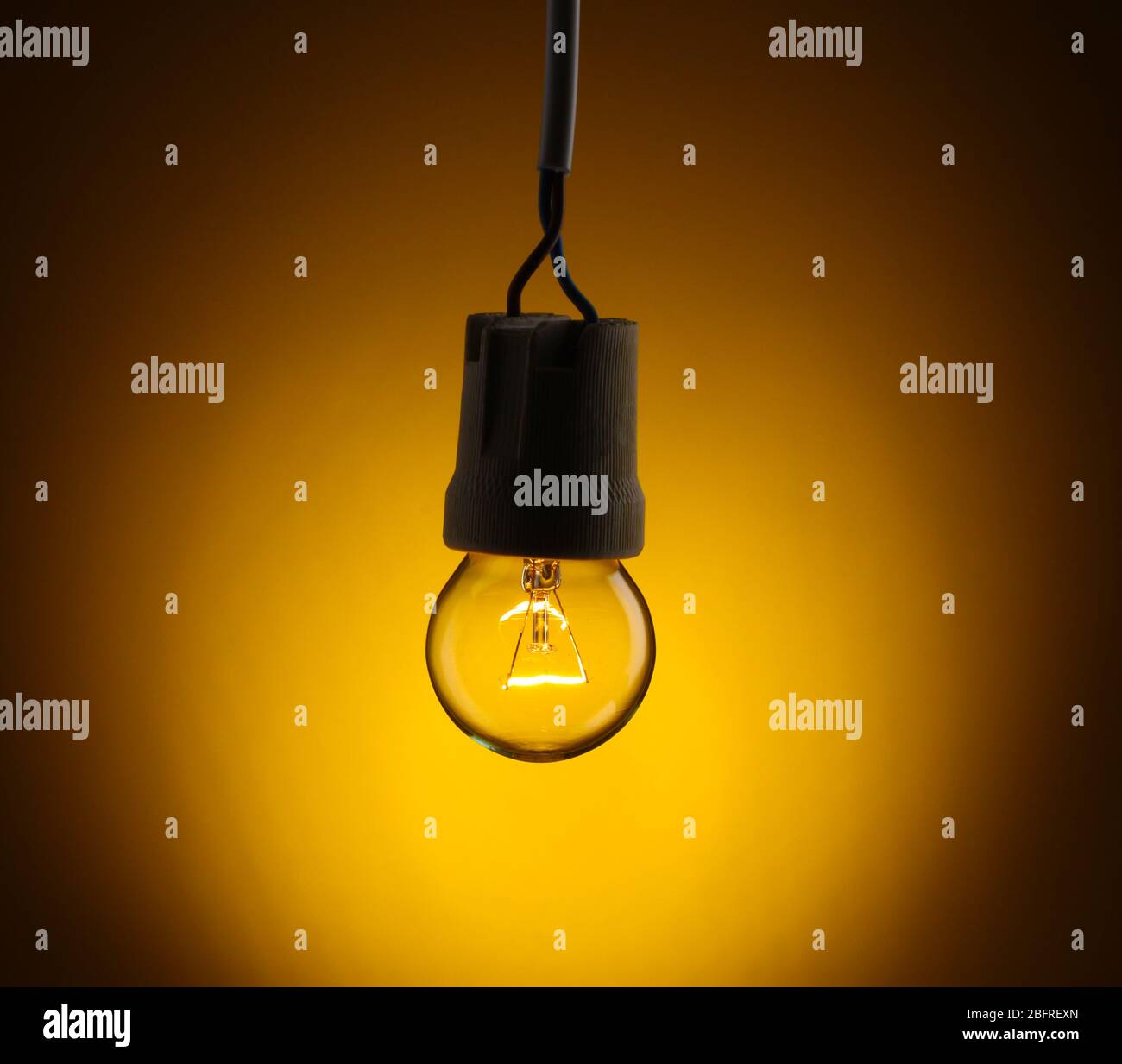 A lit light bulb on yellow background Stock Photo - Alamy