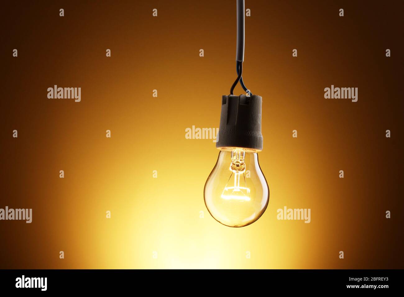 A lit light bulb on yellow background Stock Photo - Alamy