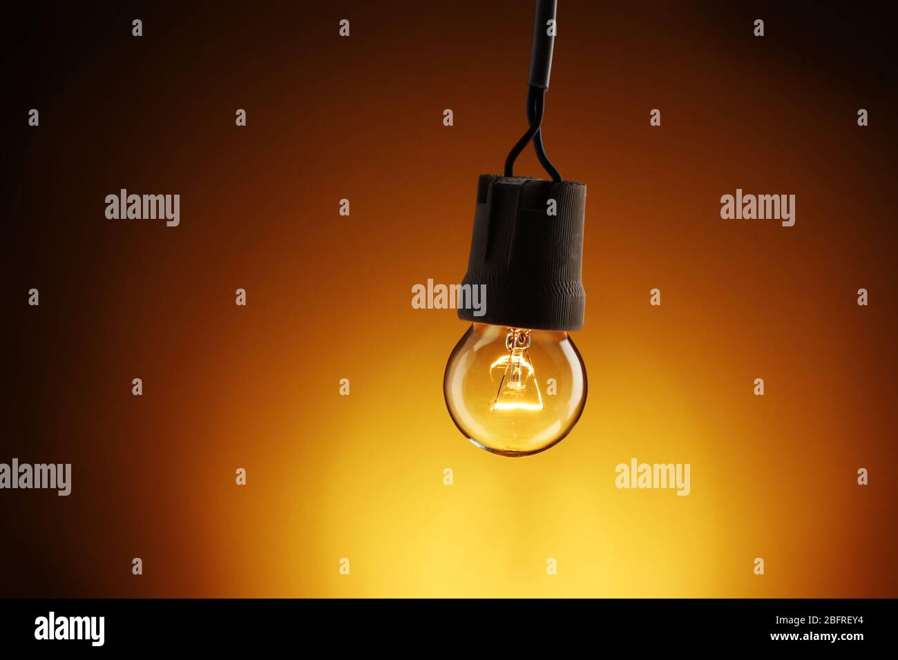 A lit light bulb on yellow background Stock Photo - Alamy