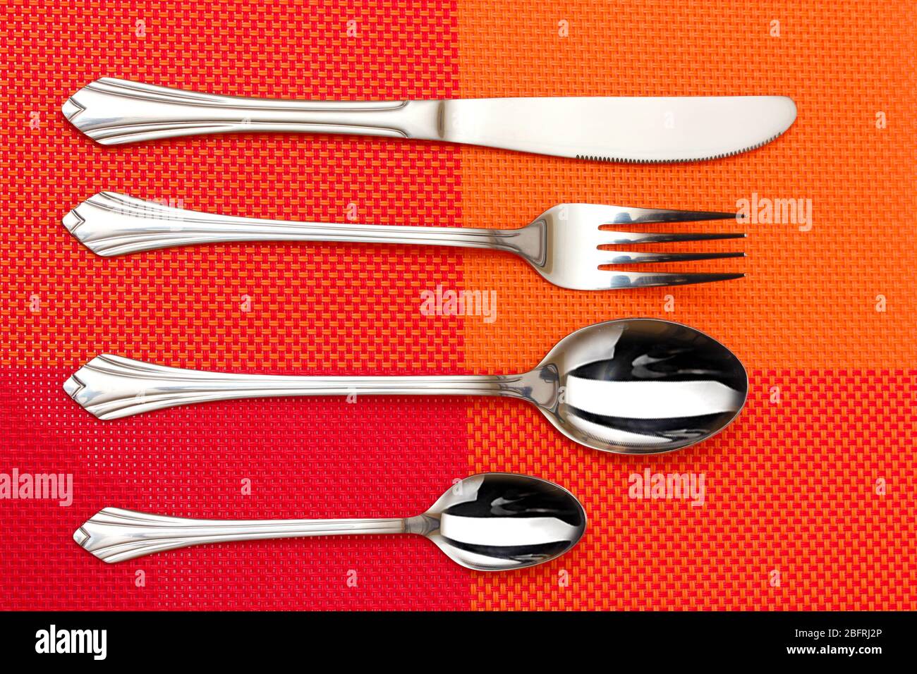 Fork, spoon and knife in a red cloth Stock Photo - Alamy