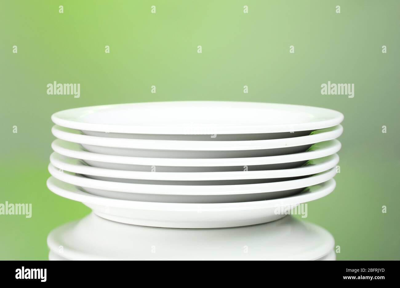 Clean plates on green background Stock Photo - Alamy