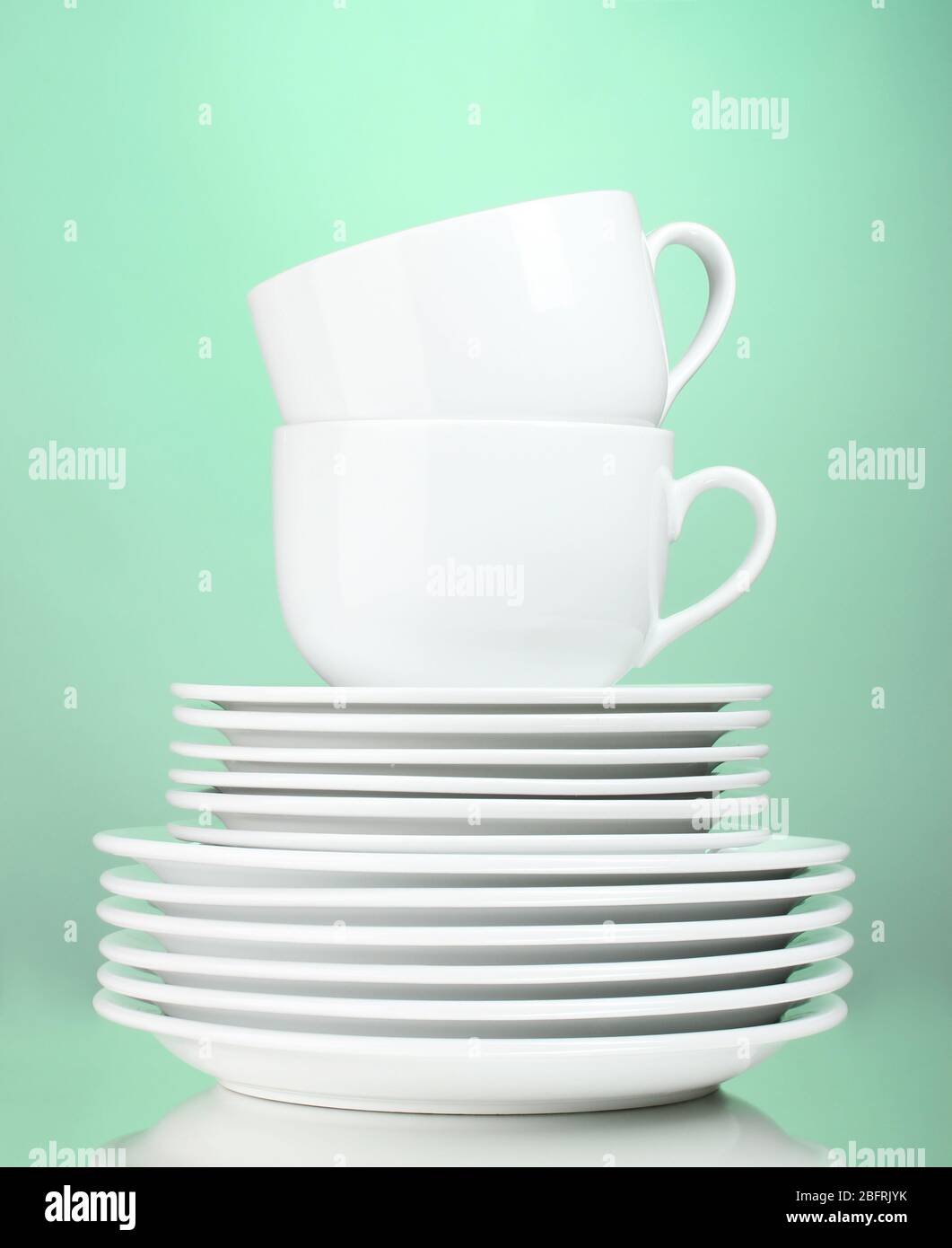 Clean plates and cups on green background Stock Photo - Alamy