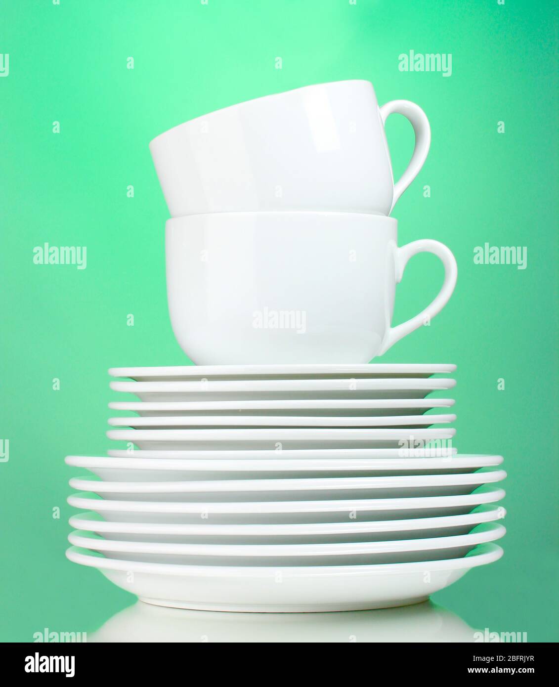 Clean plates and cups on green background Stock Photo - Alamy
