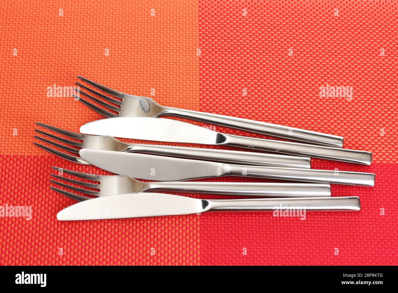 Forks and knives on a red tablecloth Stock Photo - Alamy
