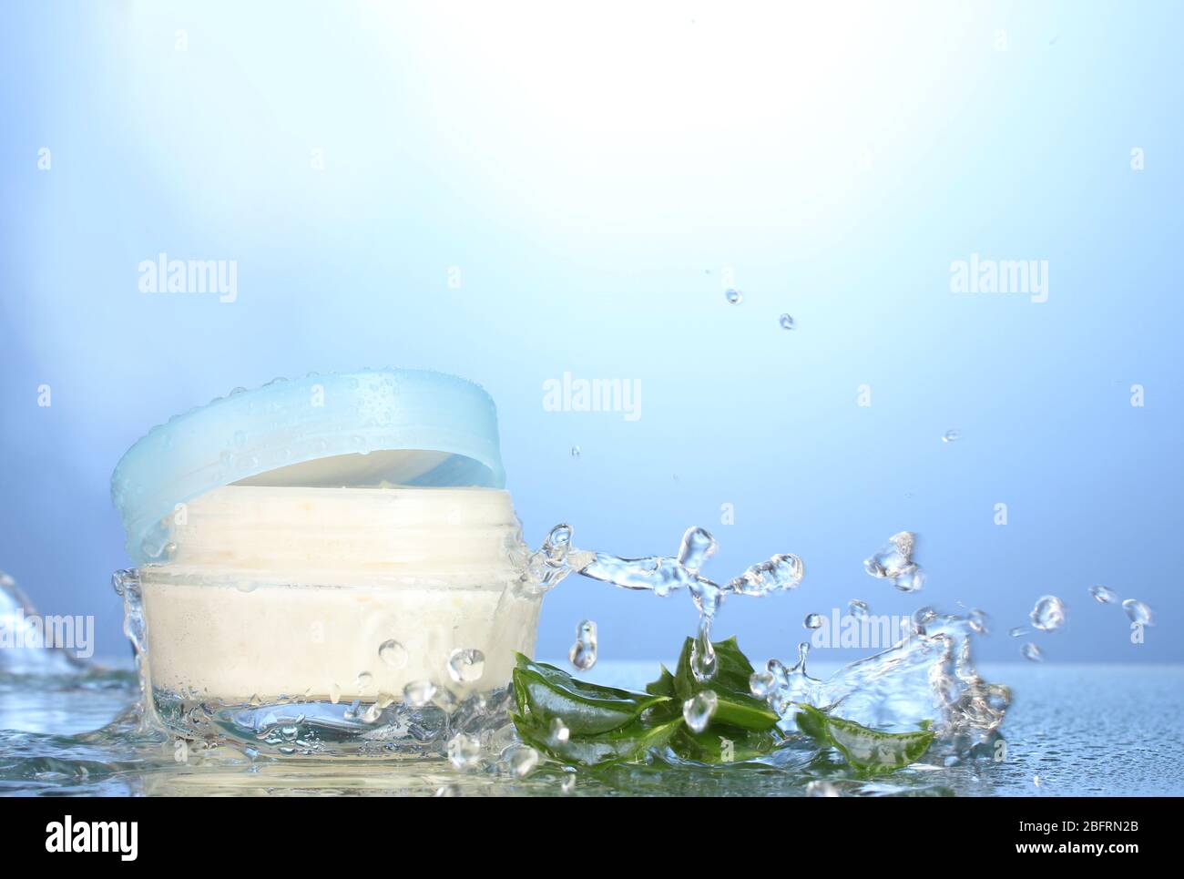 Opened jar of cream in water splash on blue background Stock Photo - Alamy