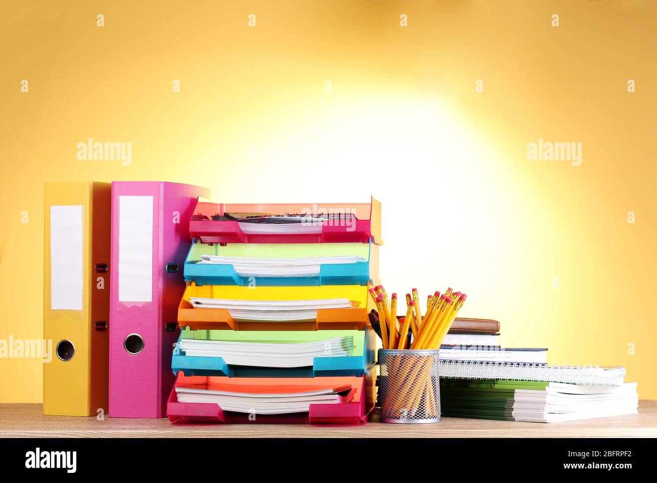 bright paper trays and stationery on wooden table on yellow background Stock Photo - Alamy