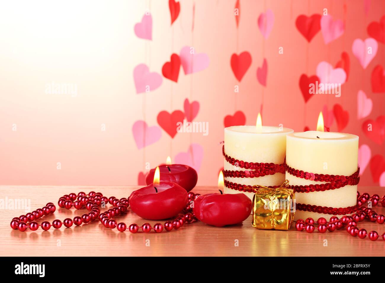 Beautiful candles with romantic decor on a wooden table on a red ...