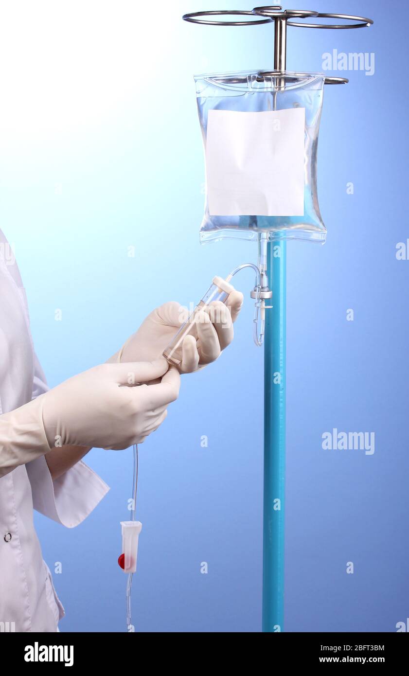 Nurse doing infusion on blue background Stock Photo - Alamy
