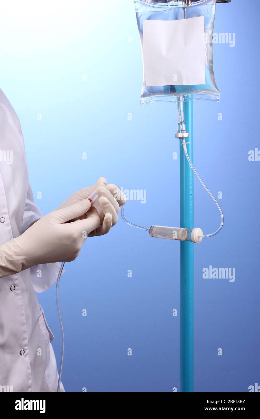 Nurse doing infusion on blue background Stock Photo - Alamy