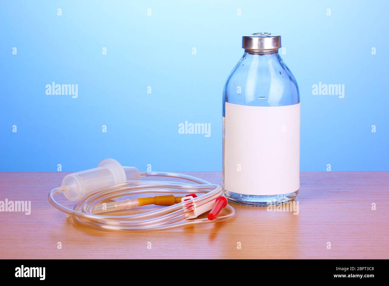 Bottle of intravenous antibiotics and plastic infusion set on wooden ...