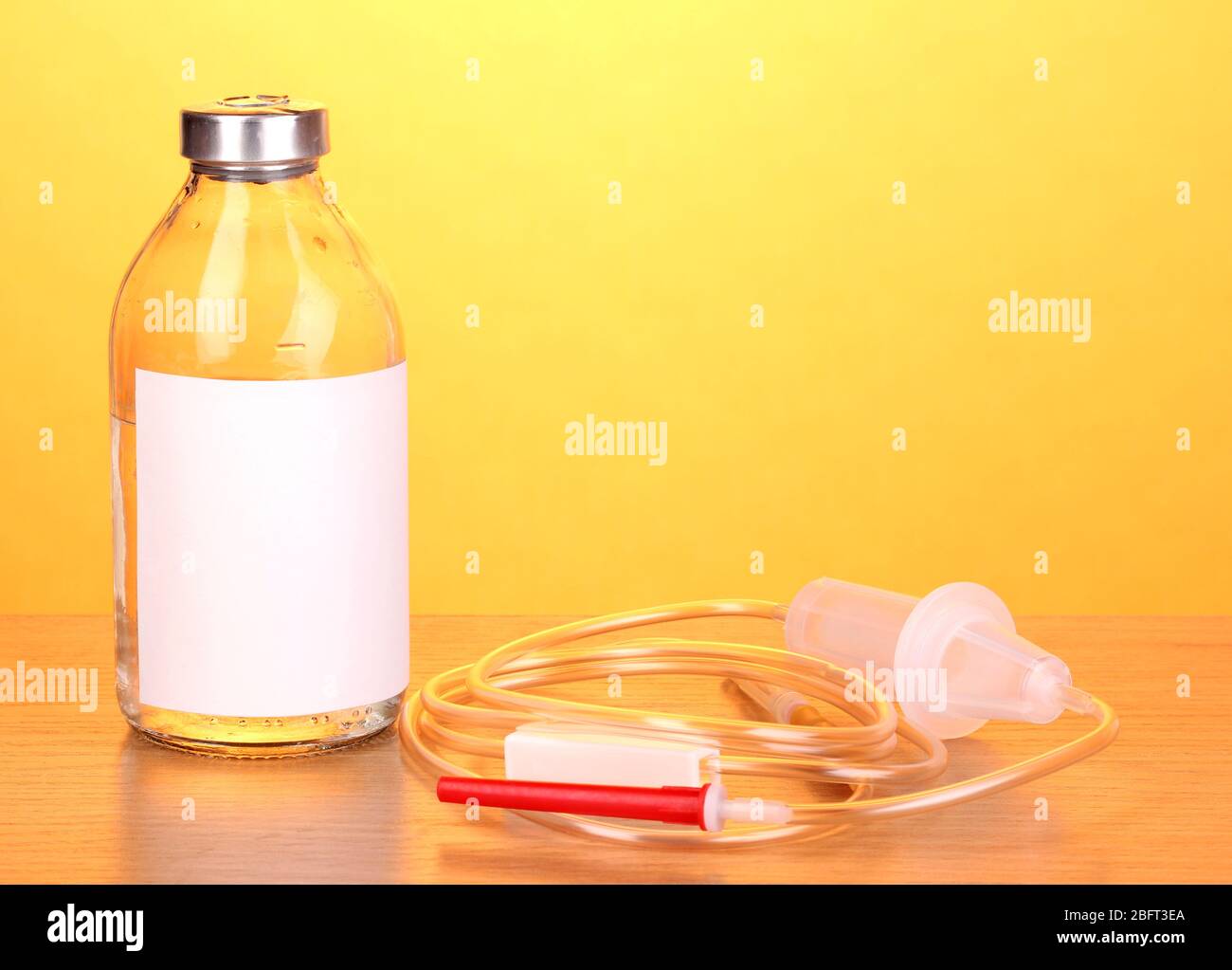 Bottle of intravenous antibiotics and plastic infusion set on wooden ...