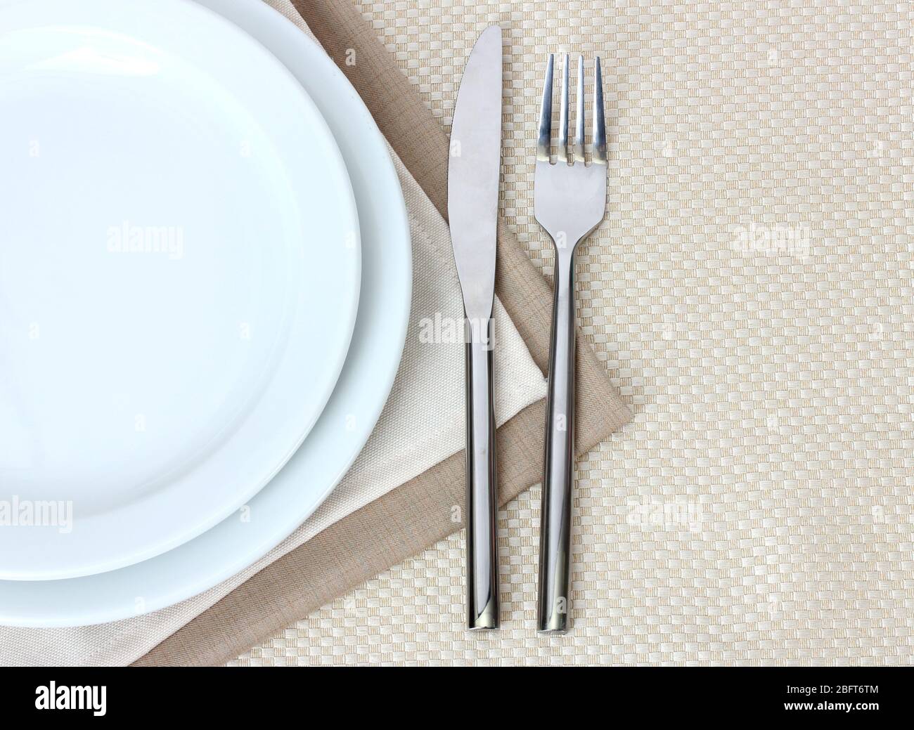 Table setting with fork, knife, plates, and napkin Stock Photo - Alamy