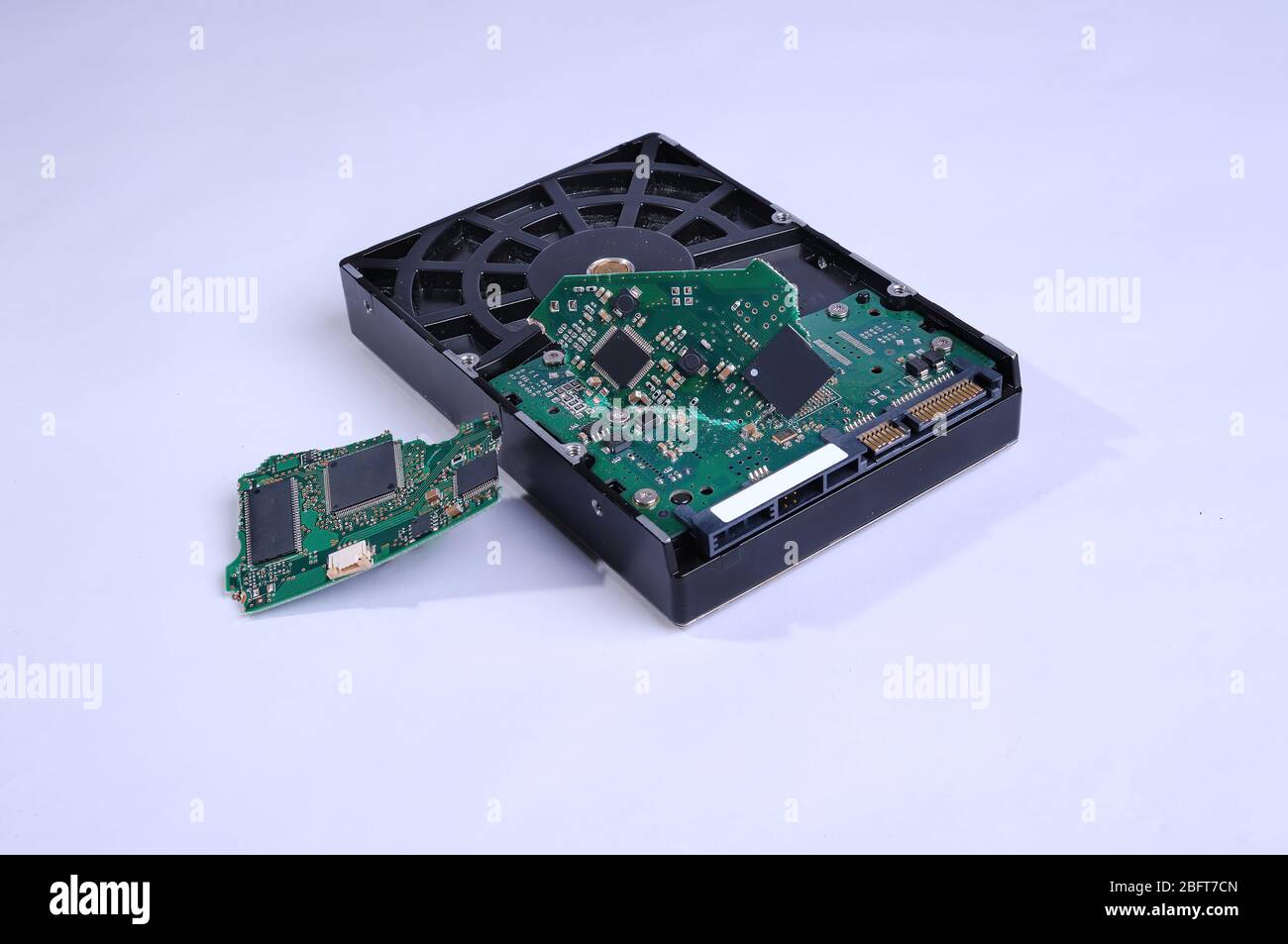 Broken computer hard drive and a broken circuit board at a white ...