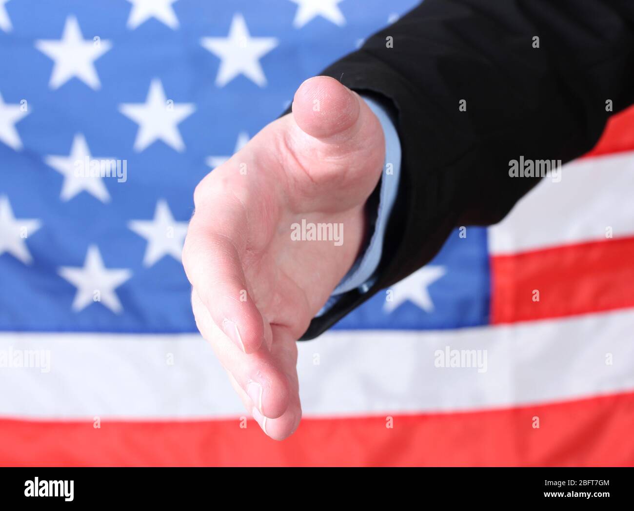 Businessman giving his hand for a handshake on American flag background ...