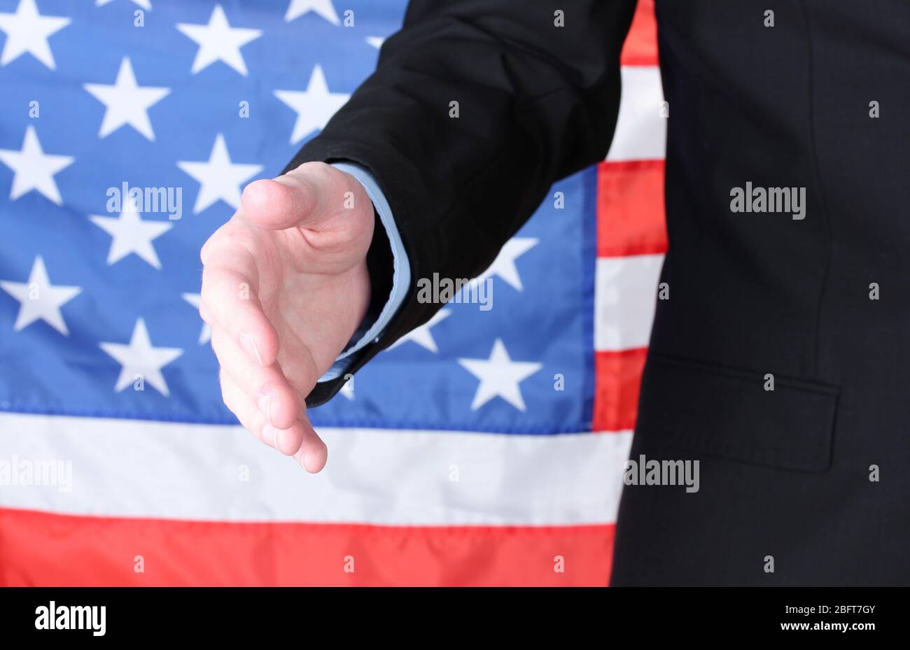 Businessman giving his hand for a handshake on American flag background ...
