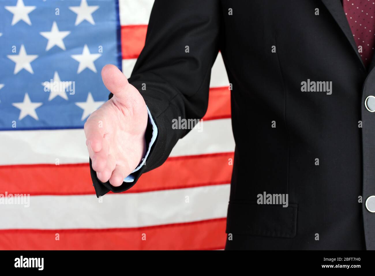 Businessman giving his hand for a handshake on American flag background ...