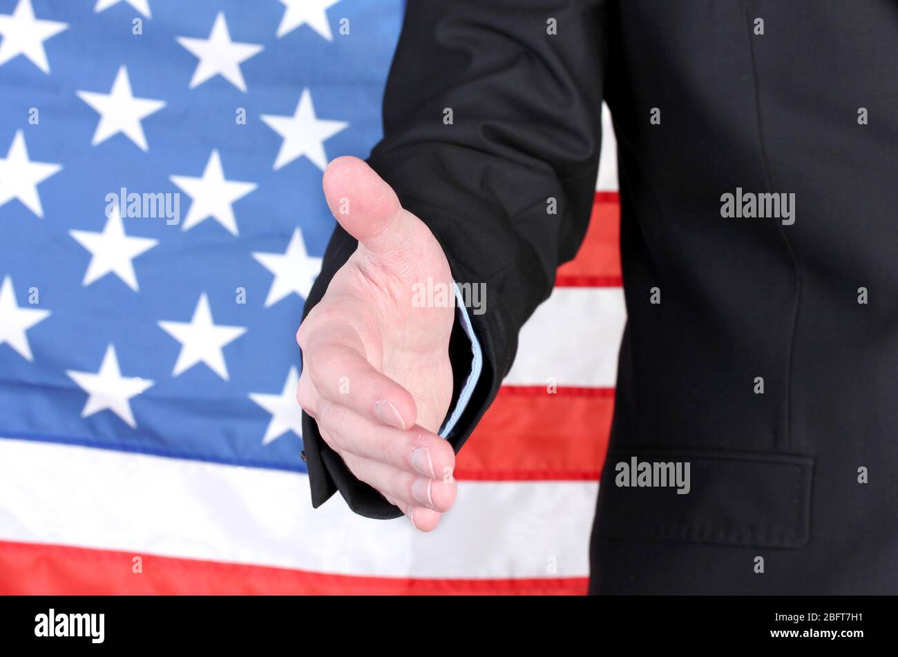 Businessman giving his hand for a handshake on American flag background ...