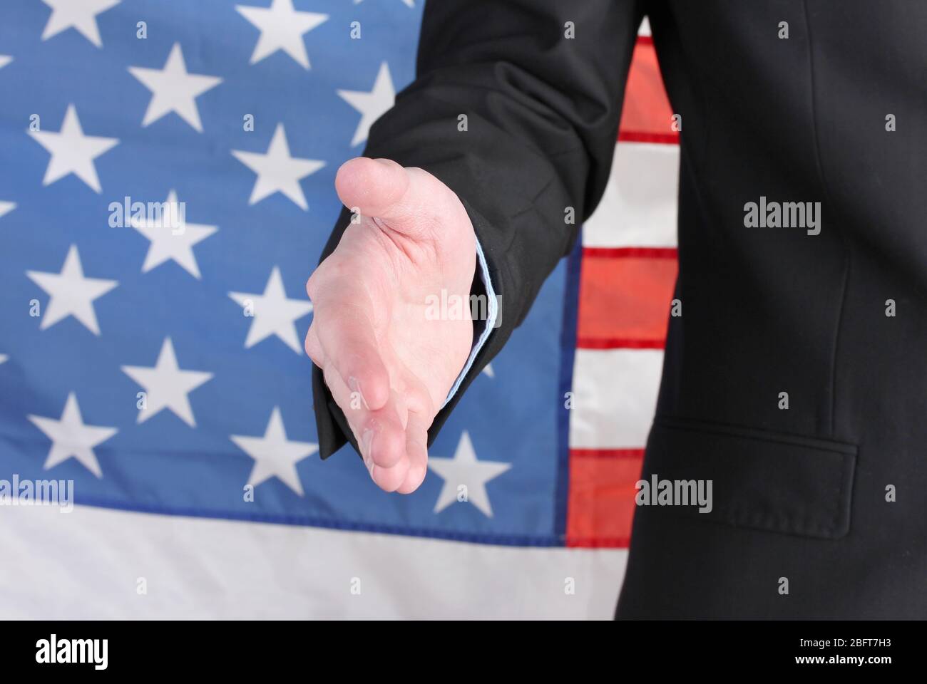 Businessman giving his hand for a handshake on American flag background ...