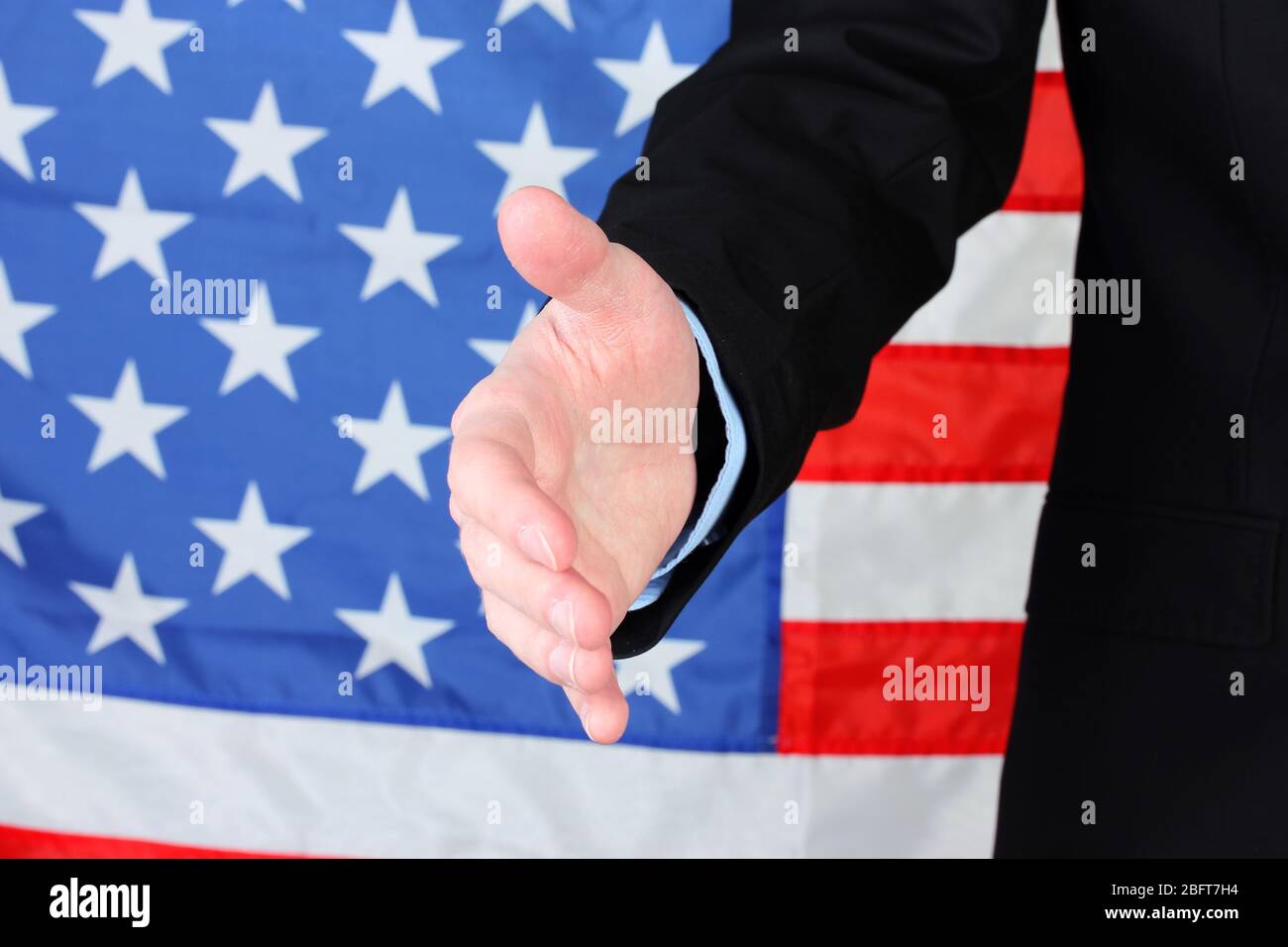 Businessman giving his hand for a handshake on American flag background ...