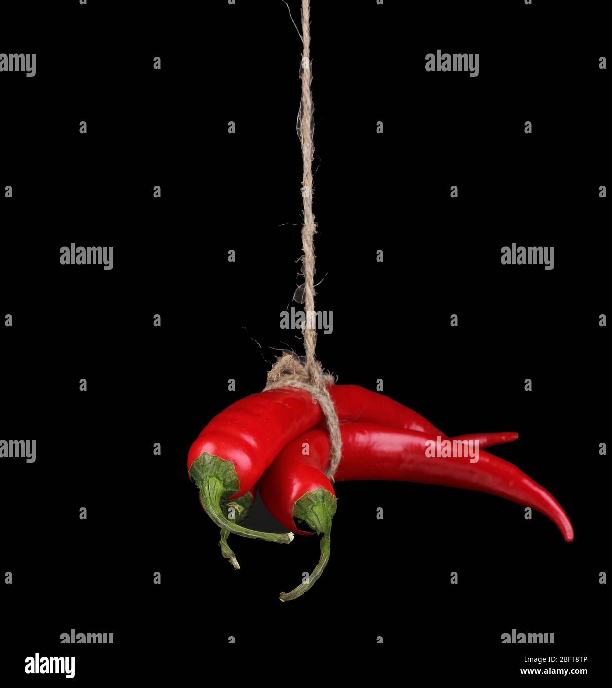 Red hot chili peppers tied with rope isolated on black Stock Photo - Alamy
