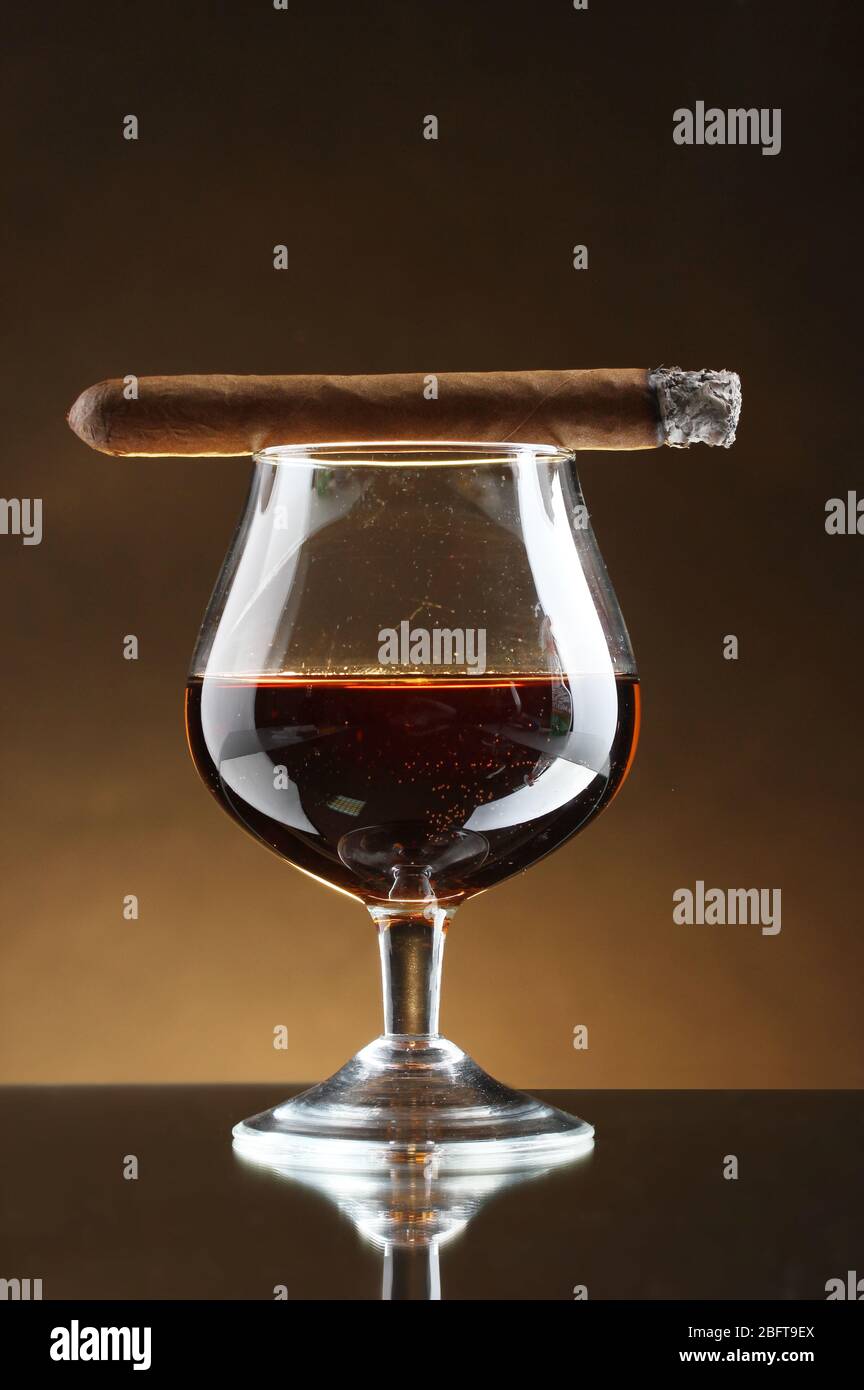 glass of brandy and cigar on brown background Stock Photo - Alamy