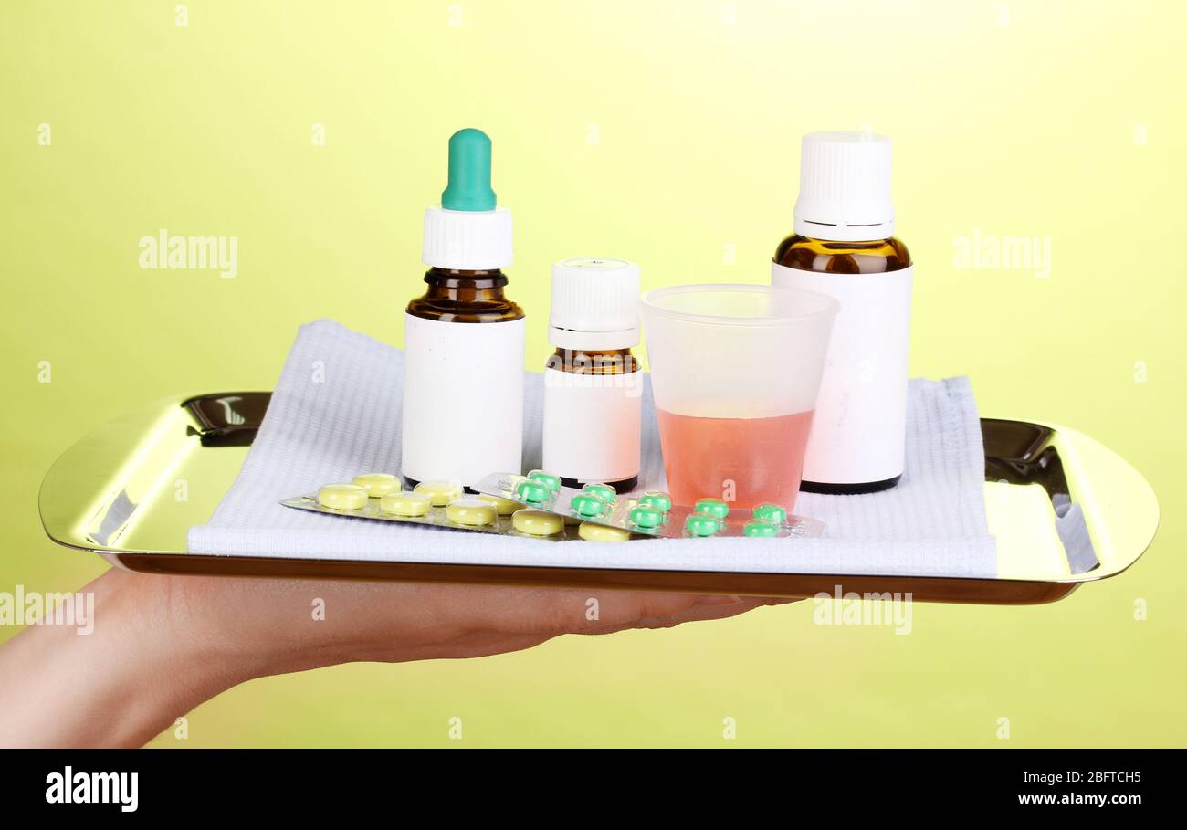 Hand holding tray with medicines on green background Stock Photo - Alamy