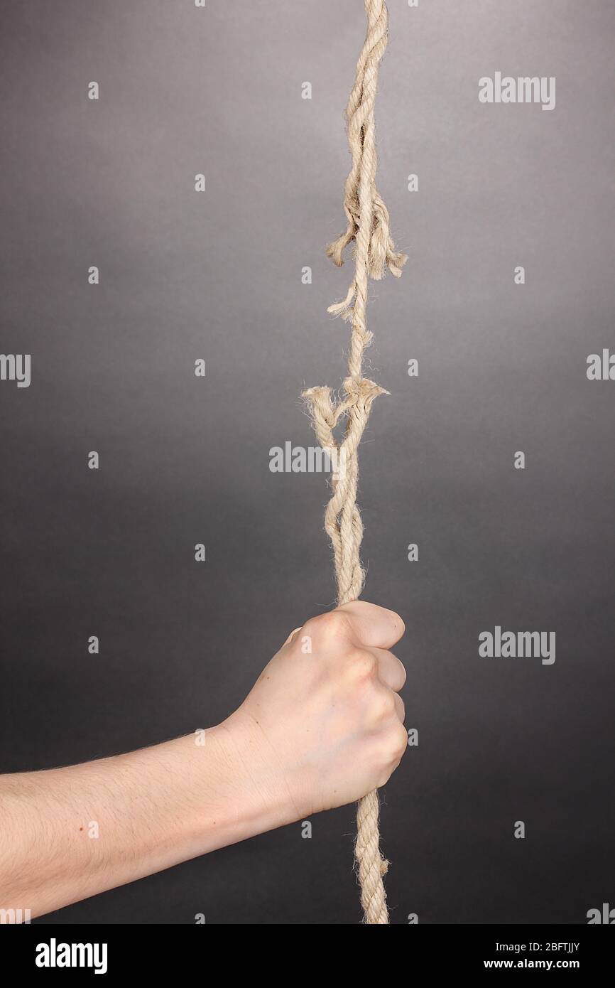Breaking rope and hand on grey background Stock Photo - Alamy