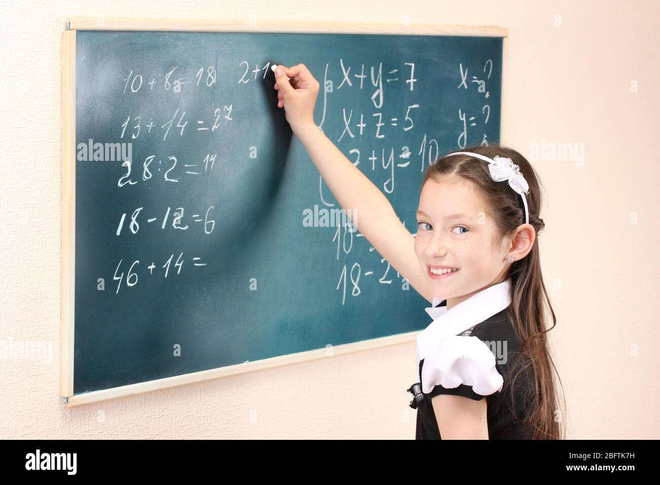 beautiful little girl writing on classroom board Stock Photo - Alamy