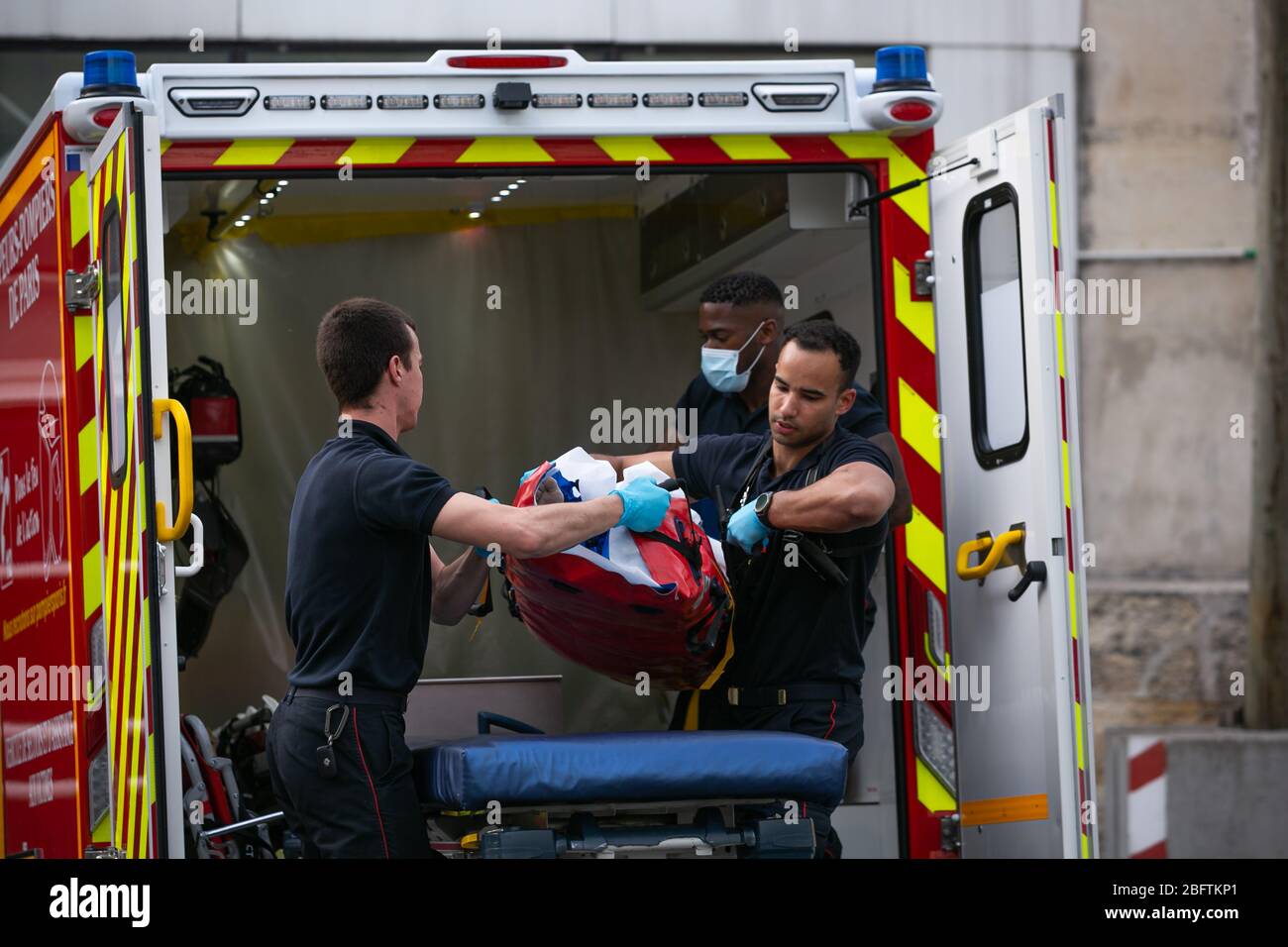 Paris, France. 19th Apr, 2020. Three paramedics lift a sick patient ...