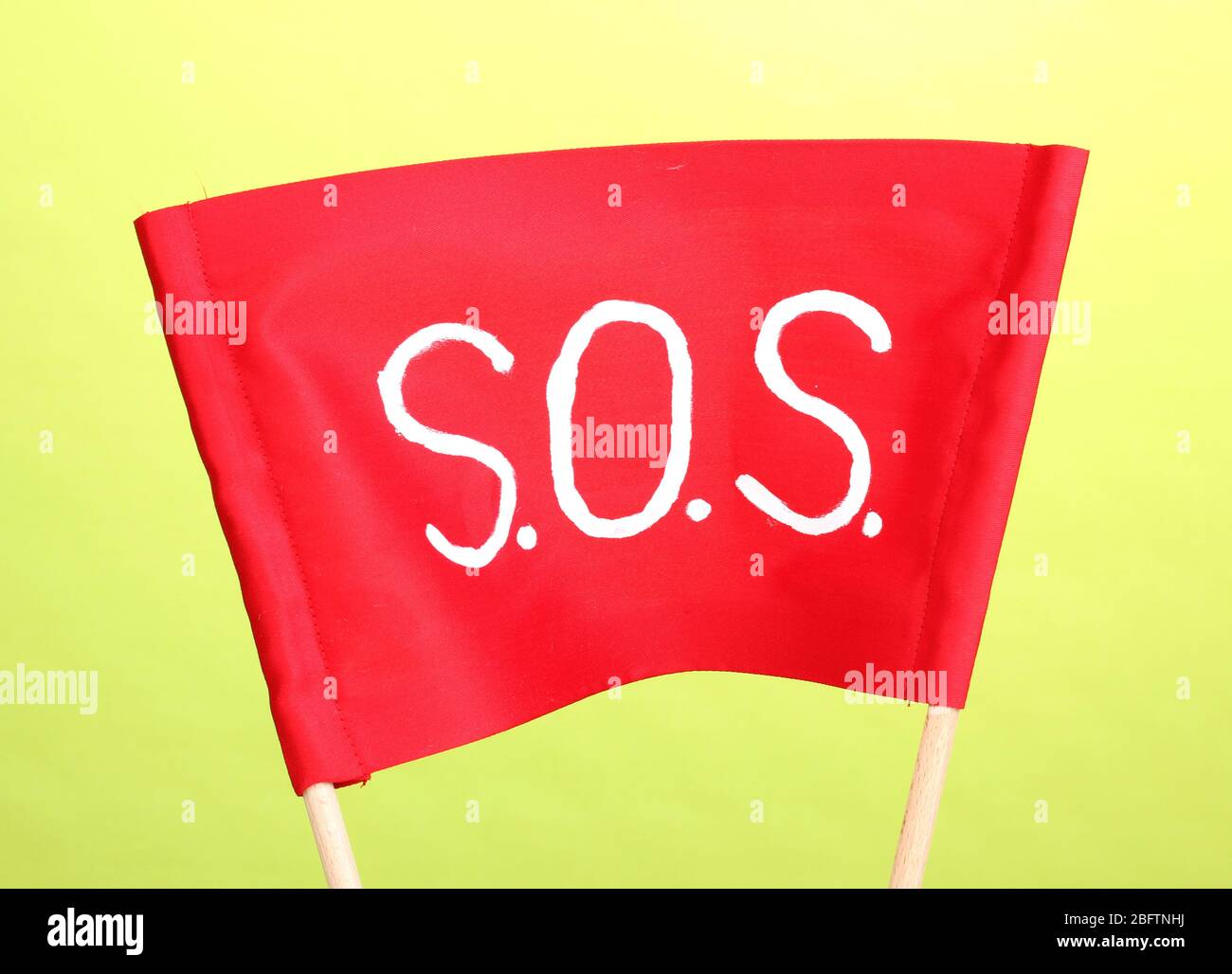 SOS signal written on red cloth on green background Stock Photo - Alamy