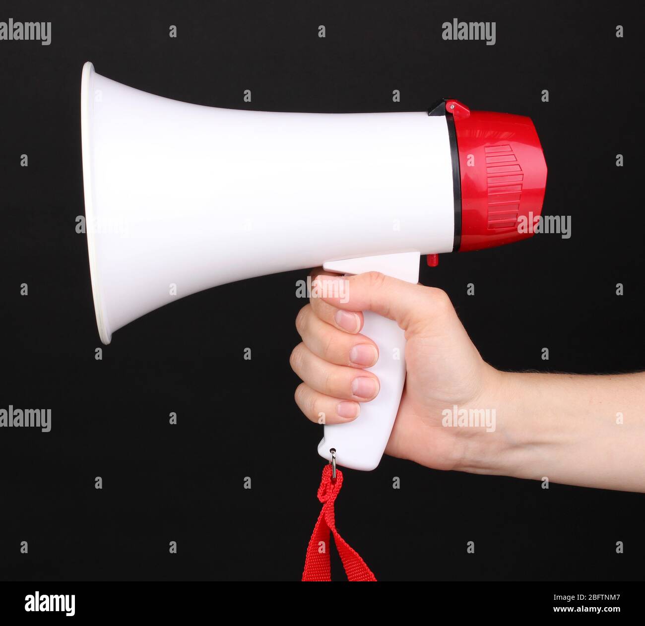 red and white megaphone in hand isolated on black Stock Photo - Alamy