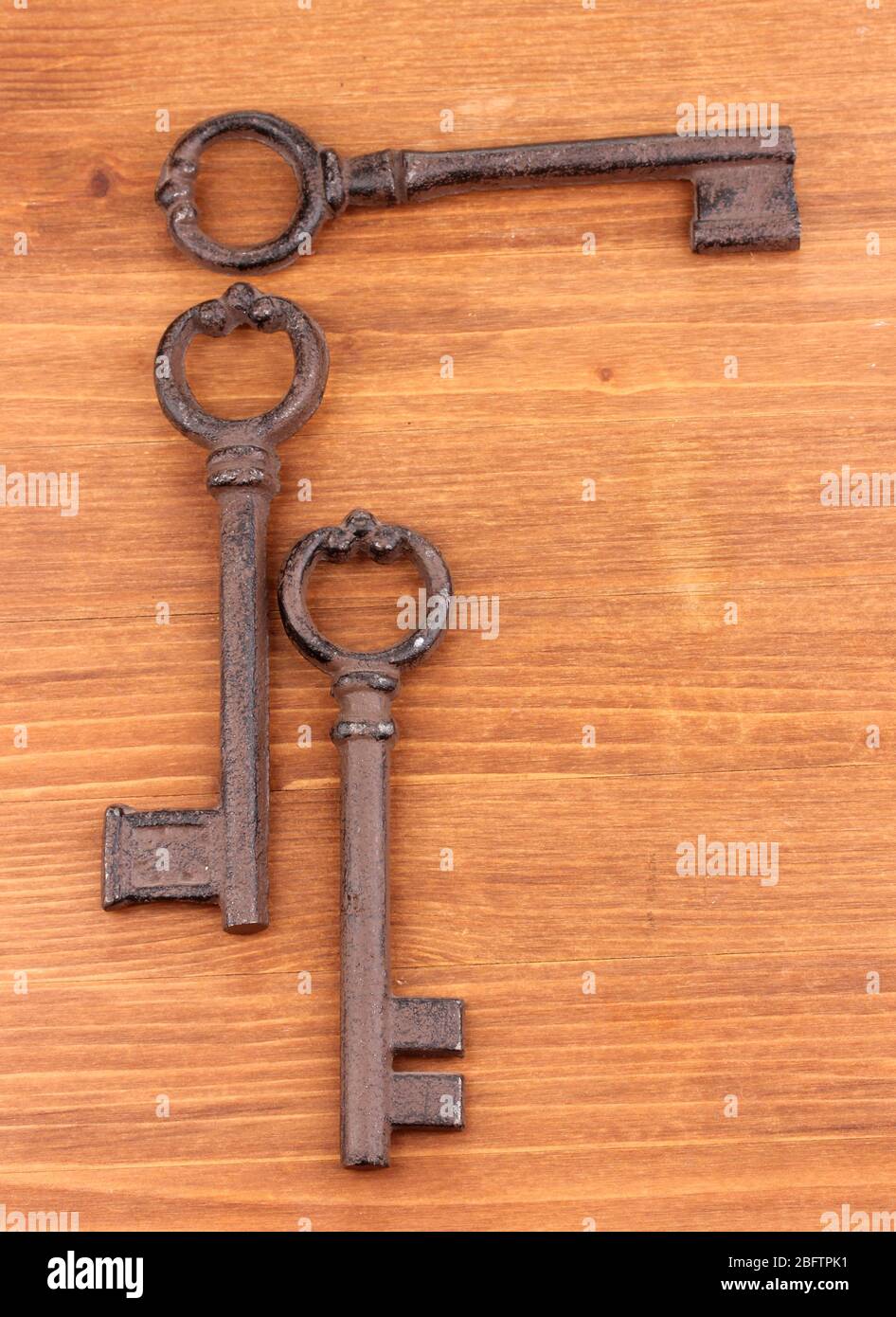 Three antique keys on wooden background Stock Photo - Alamy