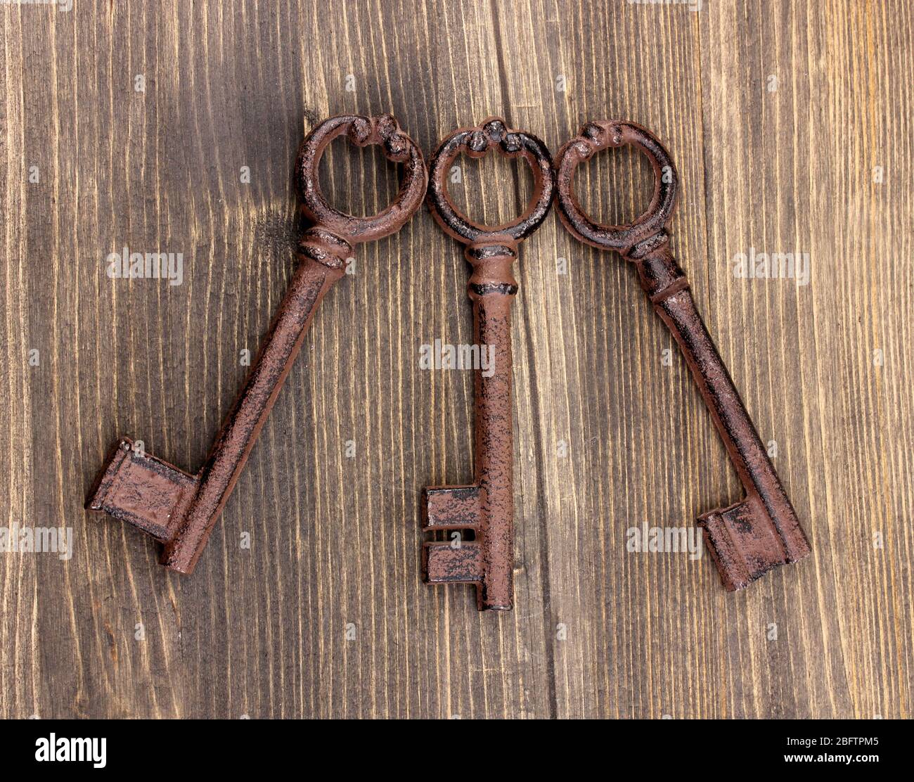 Three antique keys on wooden background Stock Photo - Alamy