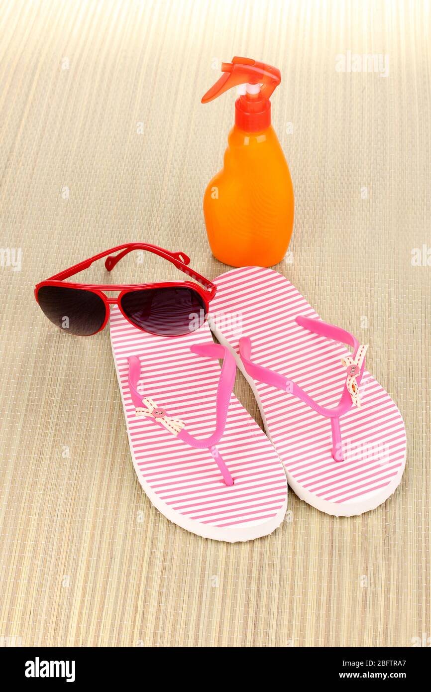 Pink beach slippers with sunglasses and sunscreen on mat Stock Photo ...