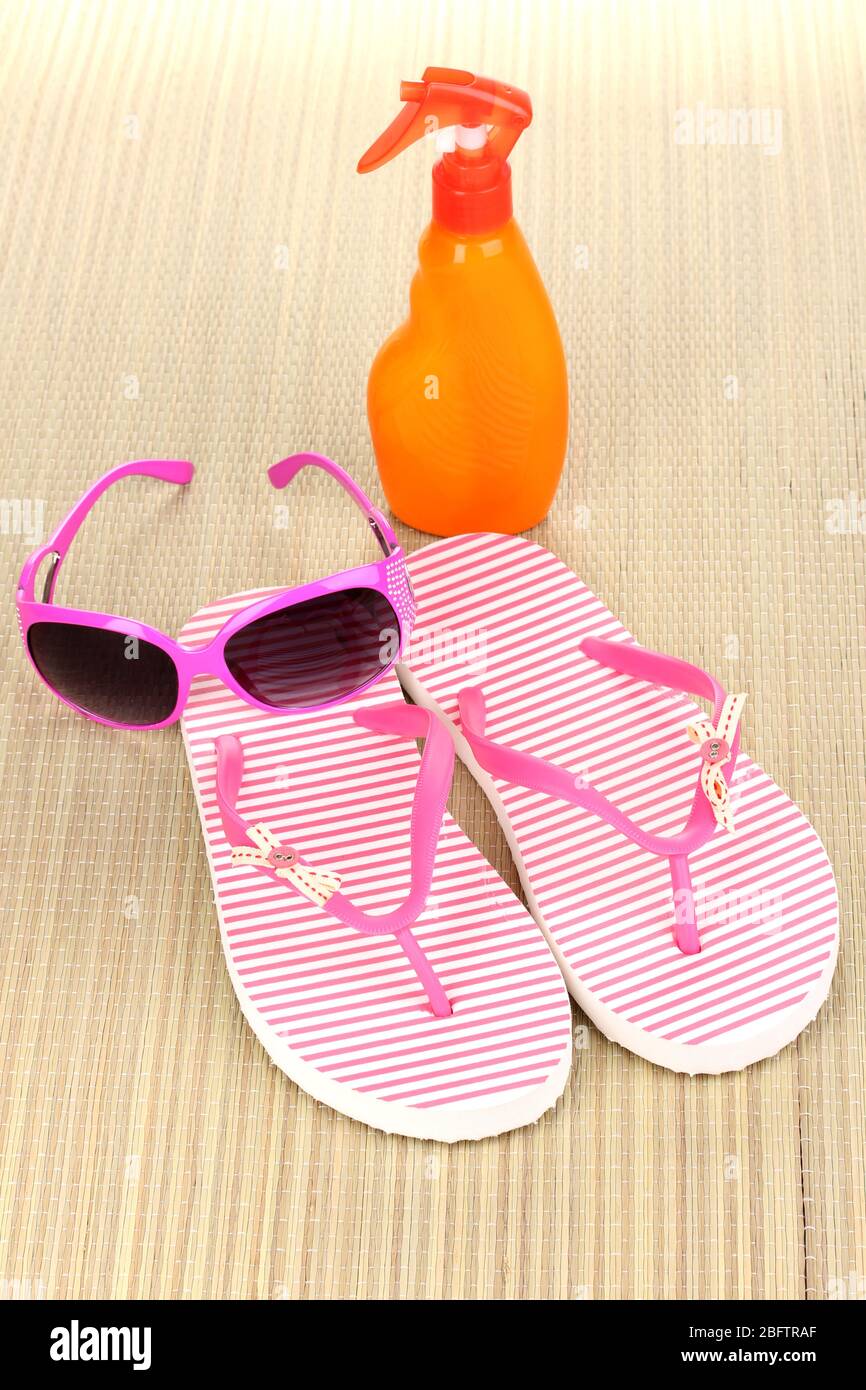 Pink beach slippers with sunglasses and sunscreen on mat Stock Photo ...