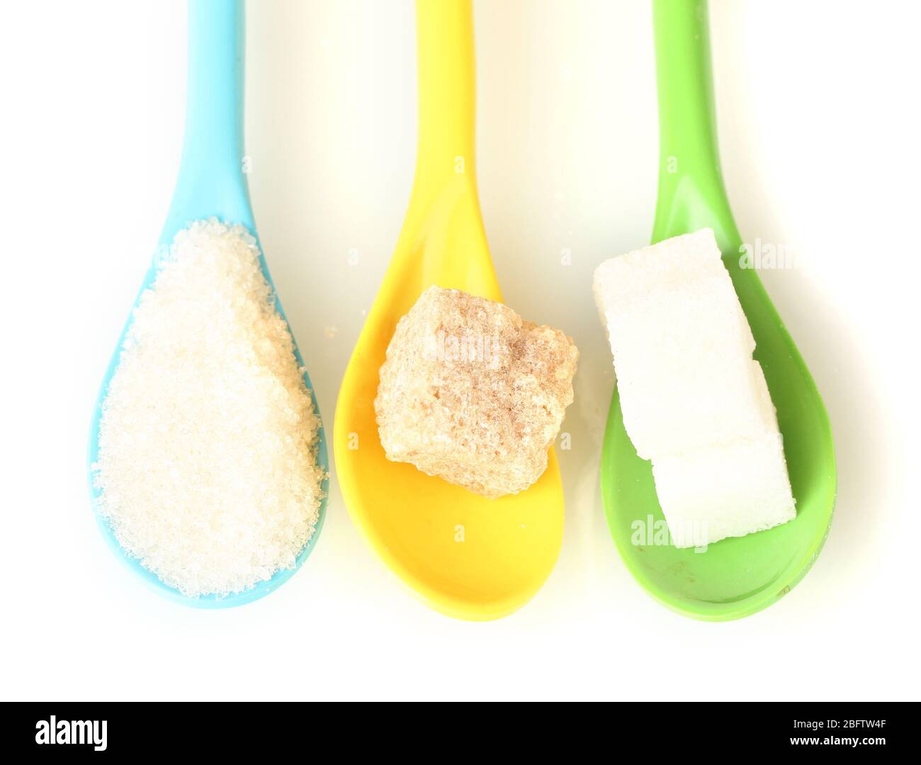 Bright colorful spoons with different types of sugar on white ...