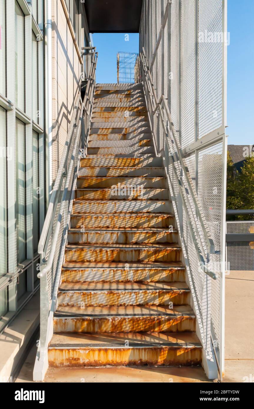 Outside metal, rusty steps with shadows from the sunshine upon them and ...