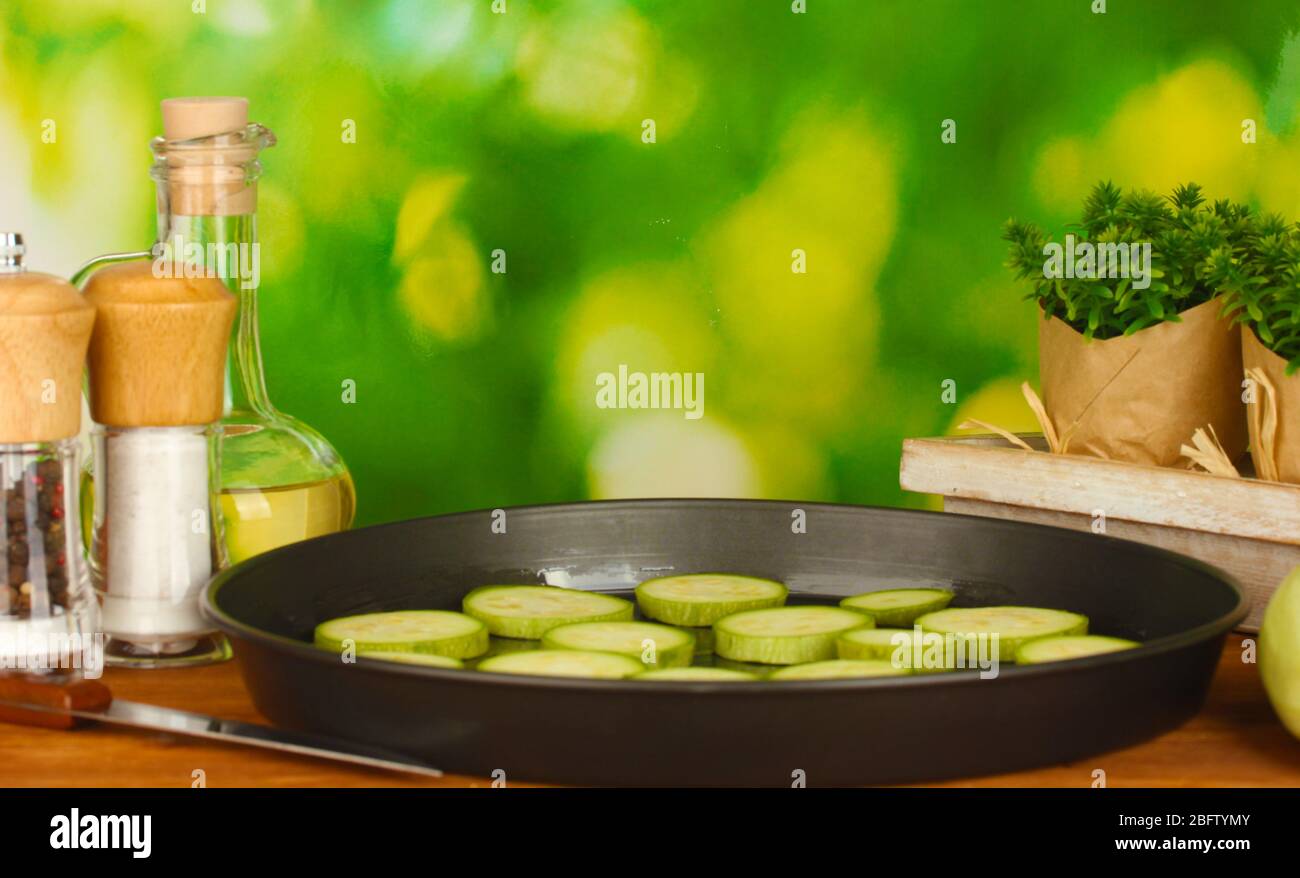 sliced squash in a pan on wooden table on green background close-up ...