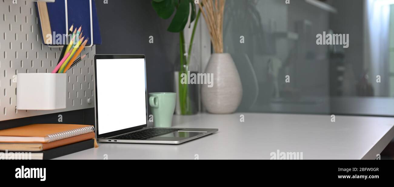 Side view of office desk with blank screen laptop, office supplies ...