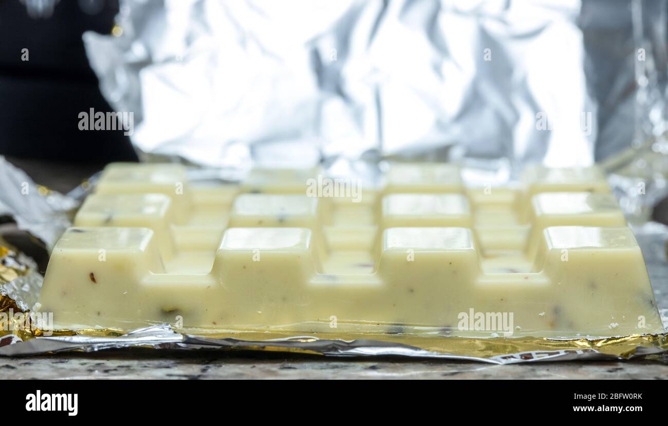 White chocolate block close-up. The package has an opened aluminum foil ...