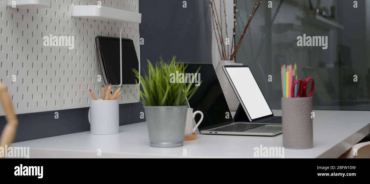 Side view of minimal office desk with mock-up digital devices, supplies ...