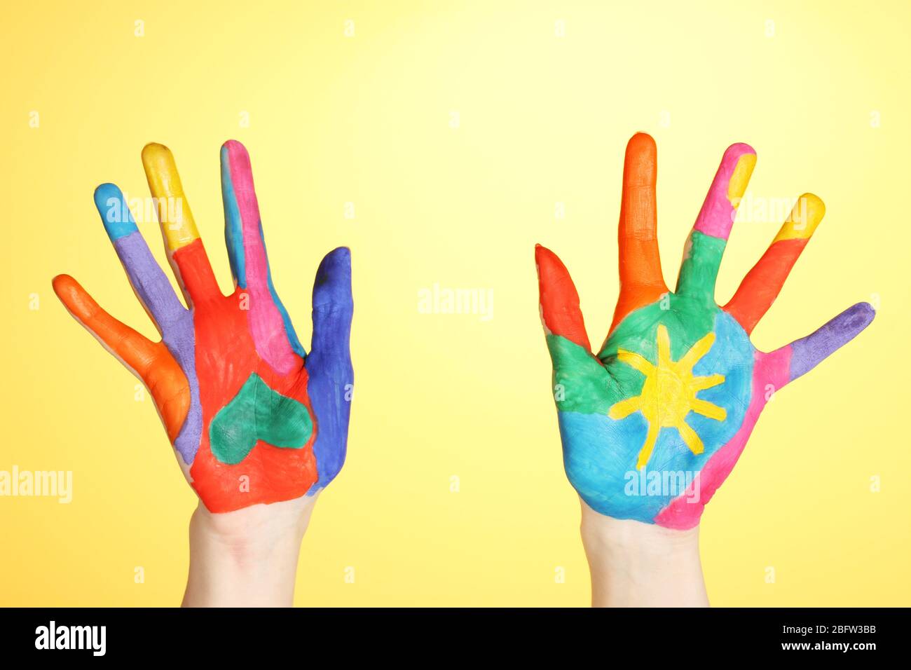 Brightly colored hands on yellow background close-up Stock Photo - Alamy