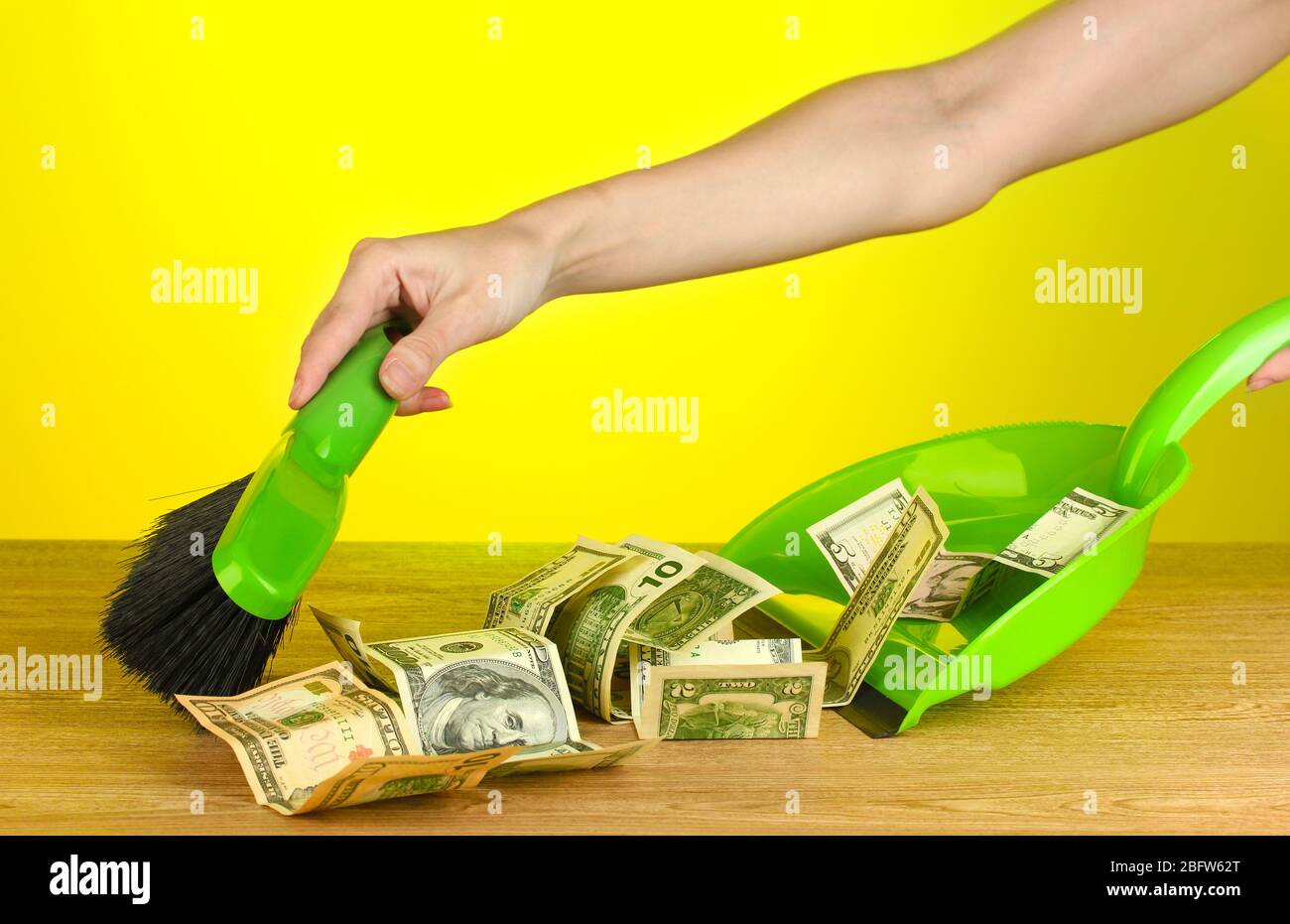 Sweeps money in the shovel on colorful background close-up Stock Photo ...
