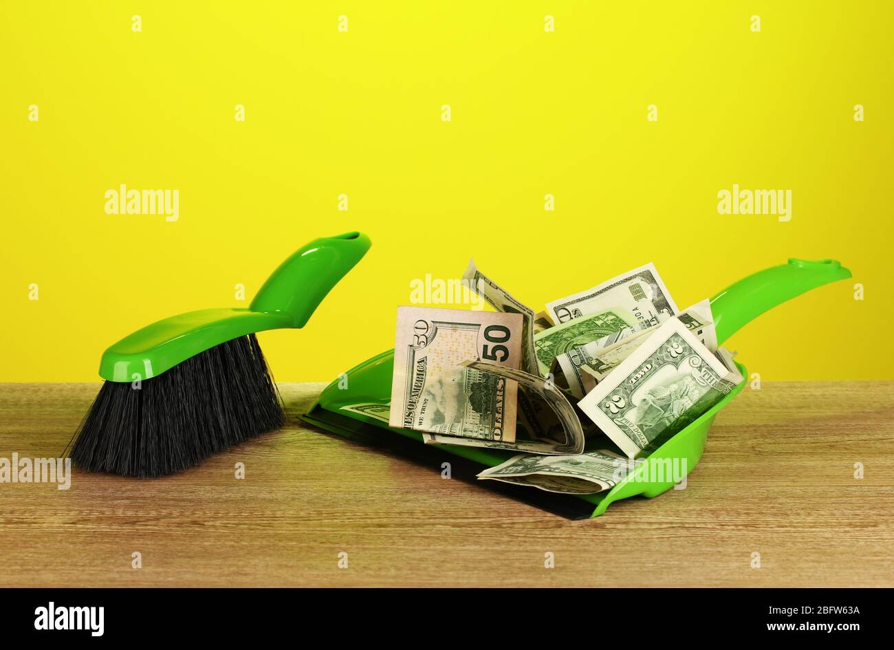 Sweeps money in the shovel on colorful background close-up Stock Photo ...