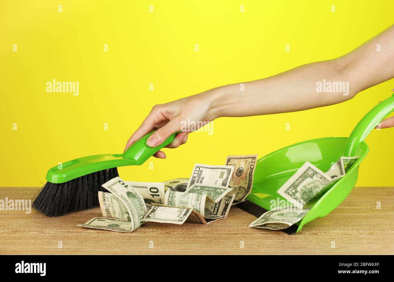 Sweeps money in the shovel on colorful background close-up Stock Photo ...