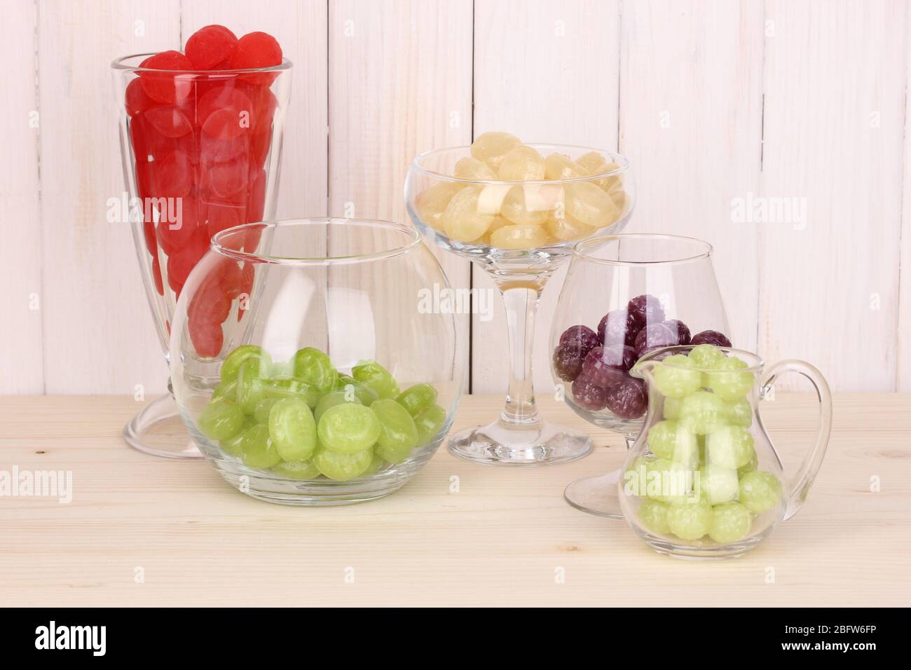 Color candies in glasses on wooden background Stock Photo - Alamy